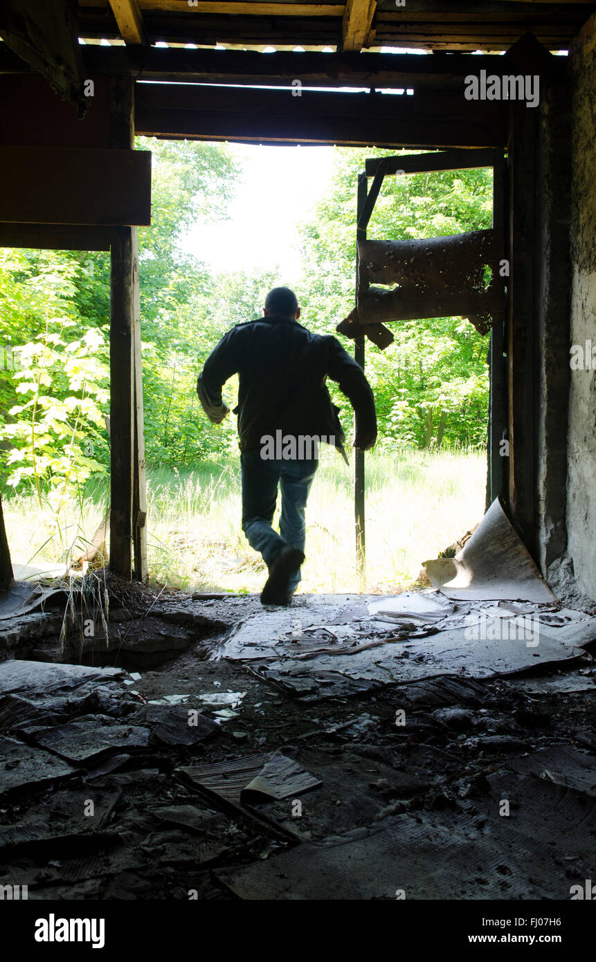 Sinister male figure running out of a derelict building Stock Photo - Alamy