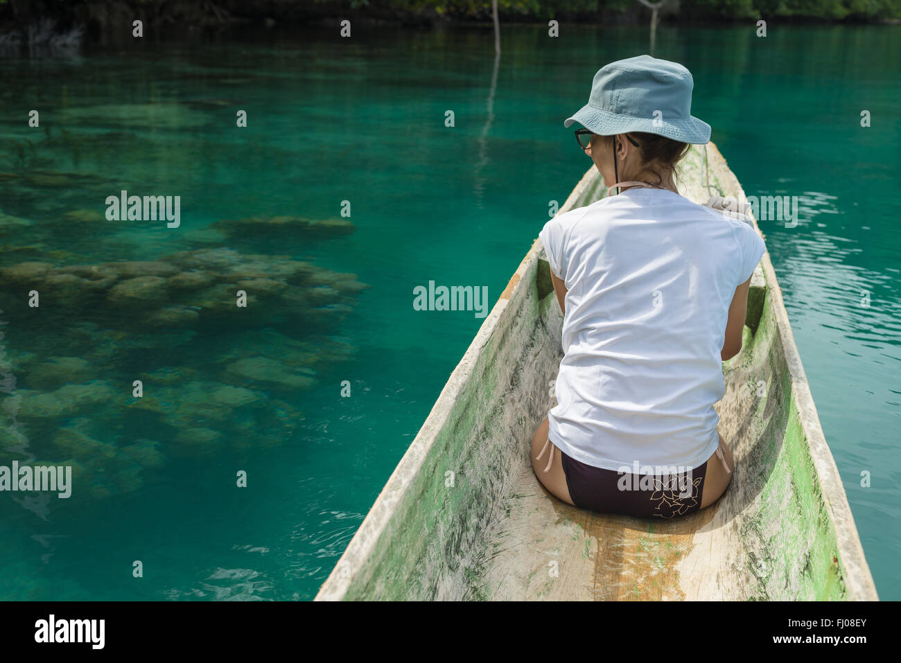 Female tourist paddling in traditional wooden canoe on blue lagoon ...
