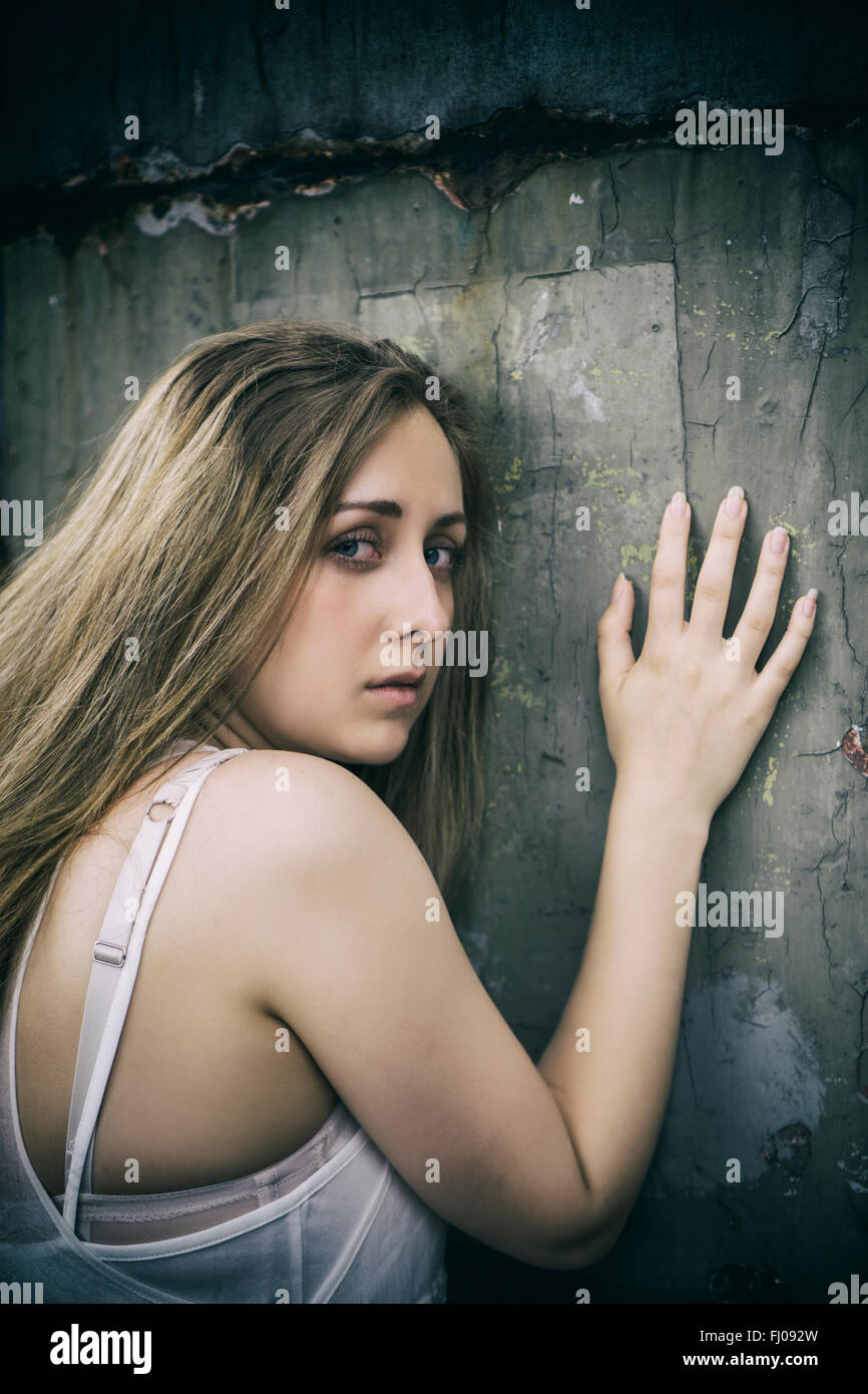 Scared young woman leaning against the wall Stock Photo - Alamy