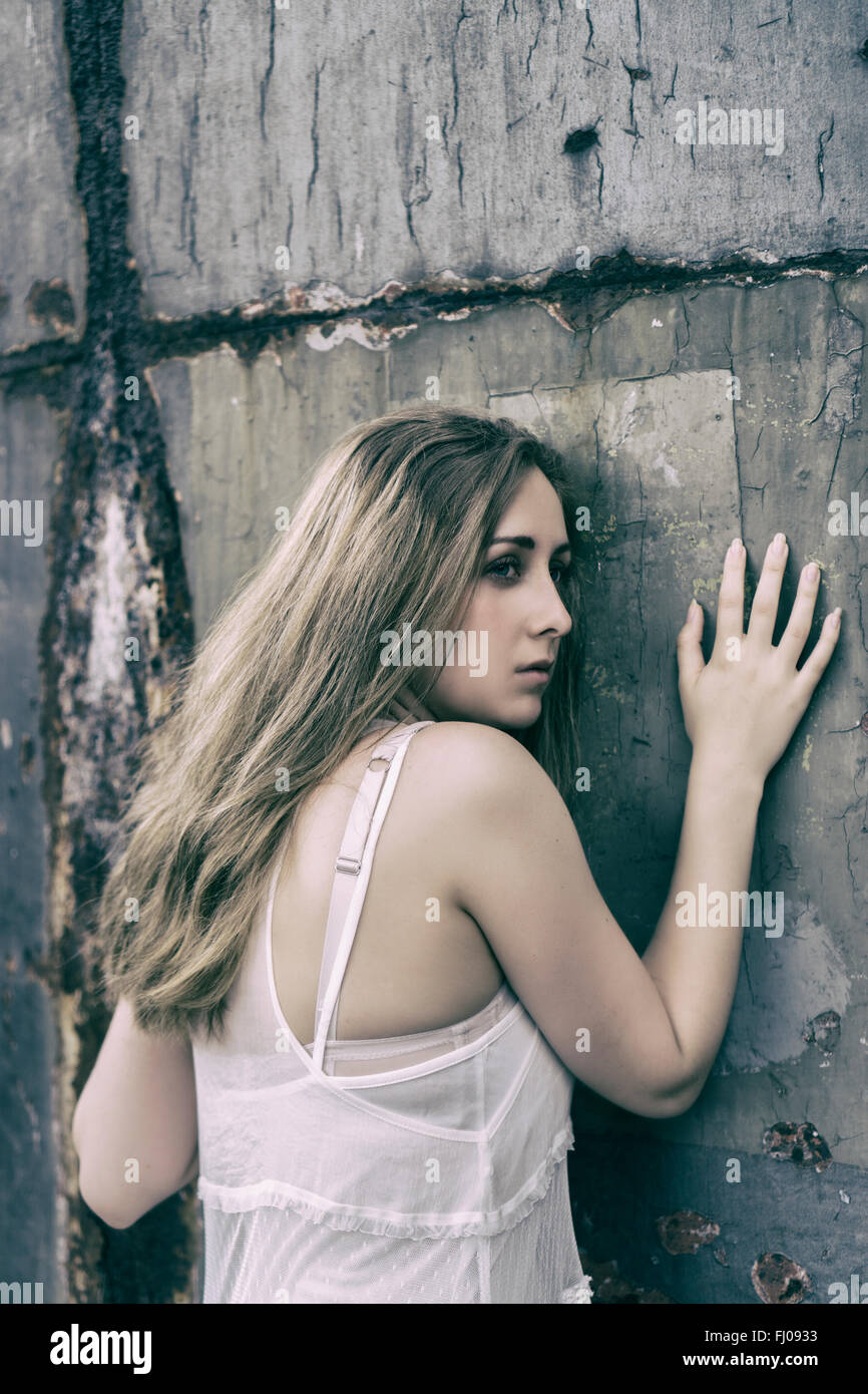 Scared young woman leaning against the wall Stock Photo - Alamy