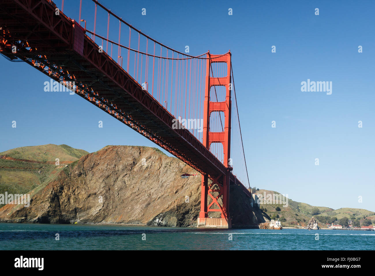 Helicopter flying under the Golden Gate Bridge on sunny day Stock Photo ...