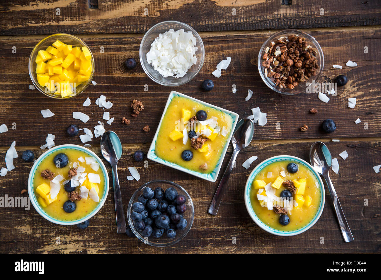 Bowls of mango smoothie with diced mango, coconut flakes, blueberries ...