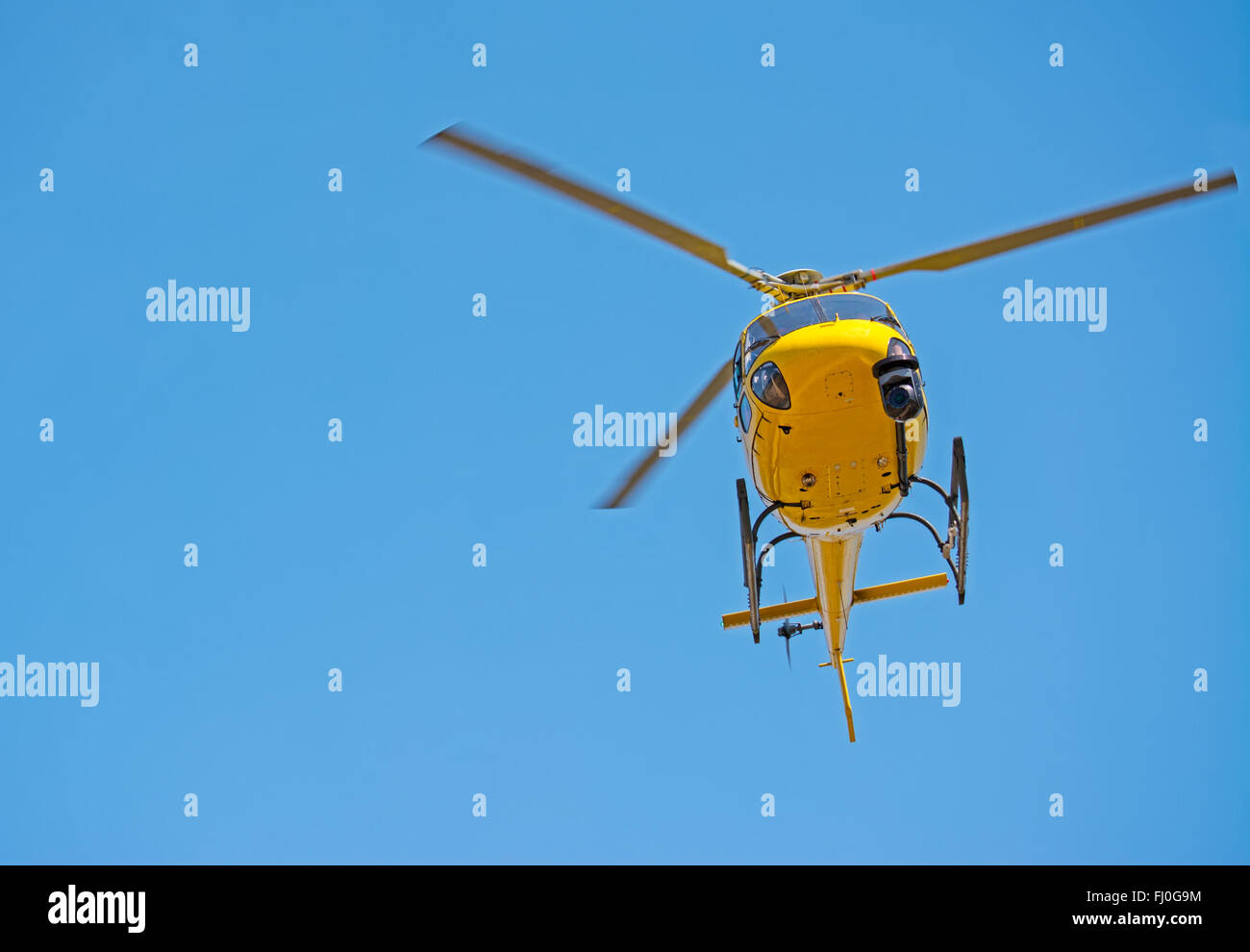 yellow helicopter flying in the blue sky Stock Photo - Alamy