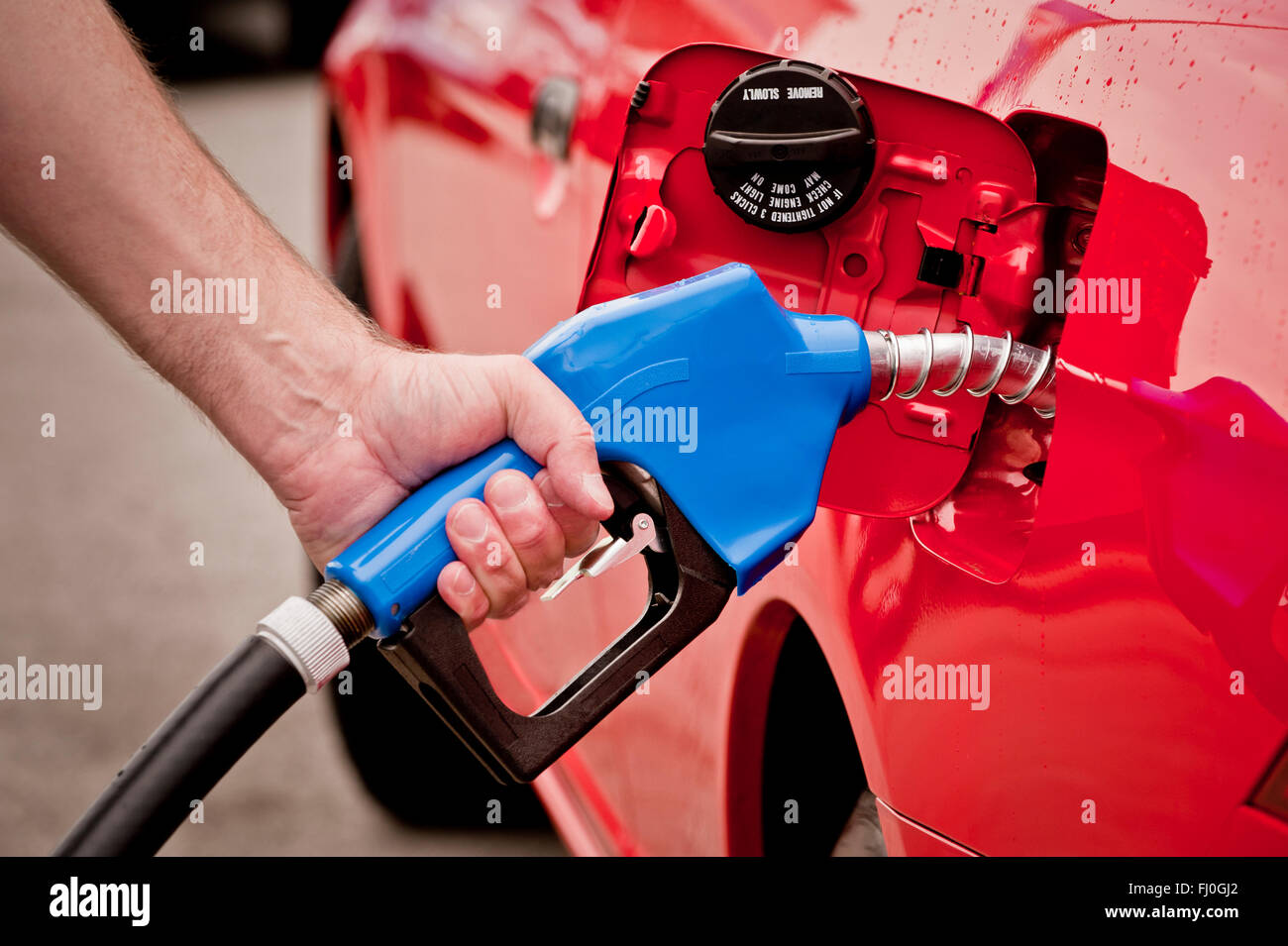 Blue Gasoline Nozzle In Red Car Stock Photo - Alamy