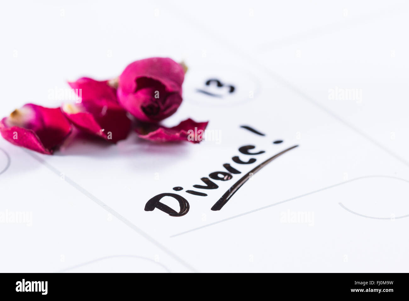 the word divorce hand written on a dry erase calendar with a dead rose ...