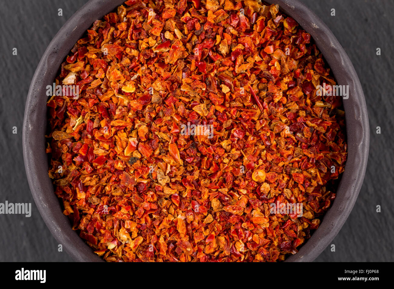 Crushed red chili pepper in stone bowl on dark background Stock Photo ...