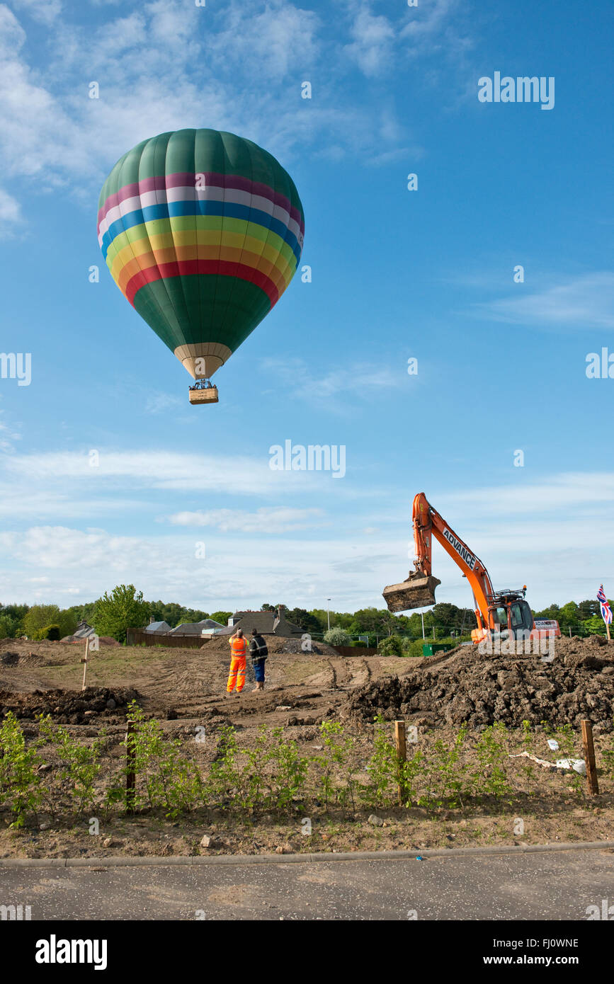 Low flying colourful balloon landing on construction site. Scottish ...