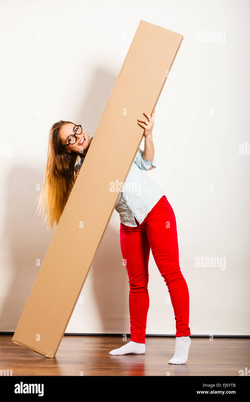 Happy woman moving into new apartment house carrying carton box with ...