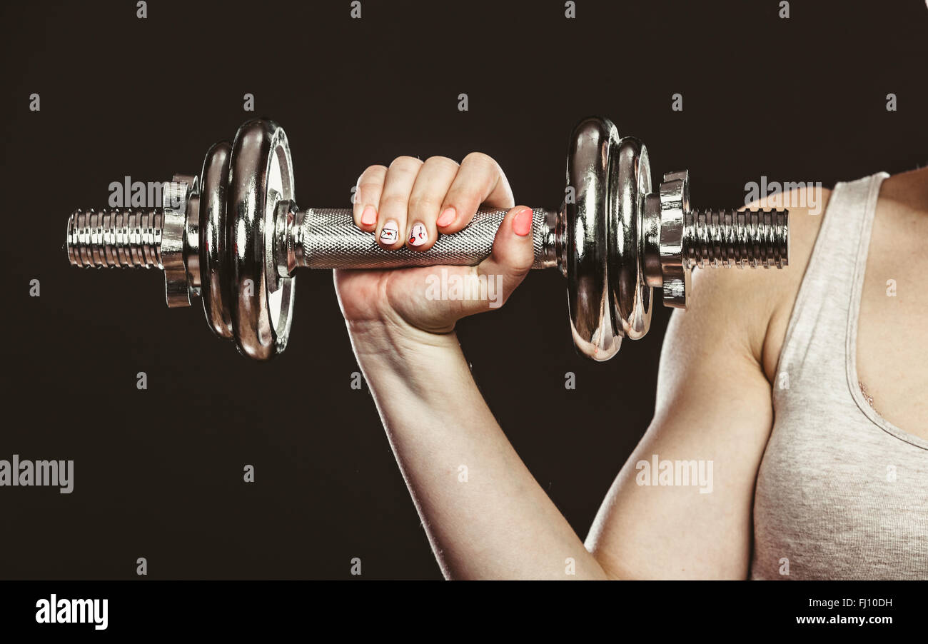Closeup of arm hand strong woman lifting dumbbells weights. Fit girl ...