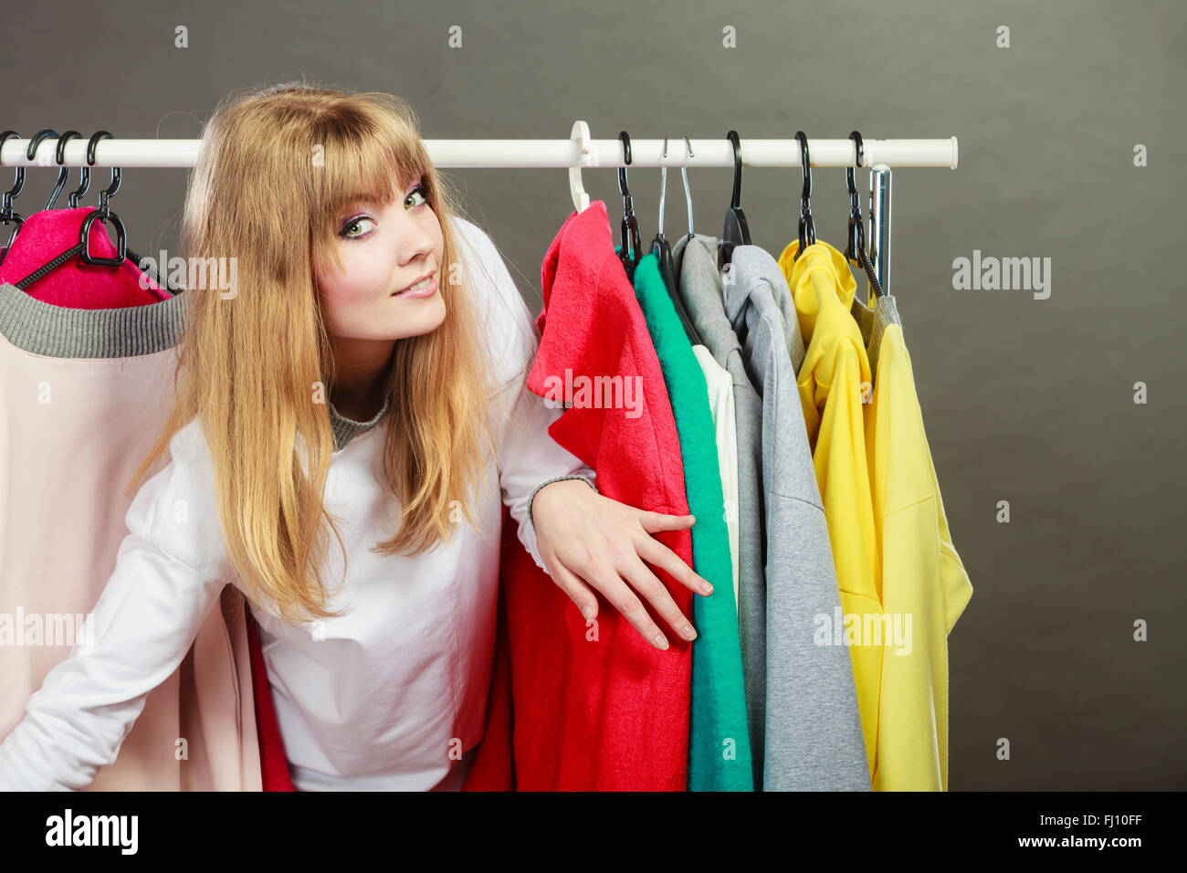 Pretty happy woman between clothing from wardrobe. Young undecided ...