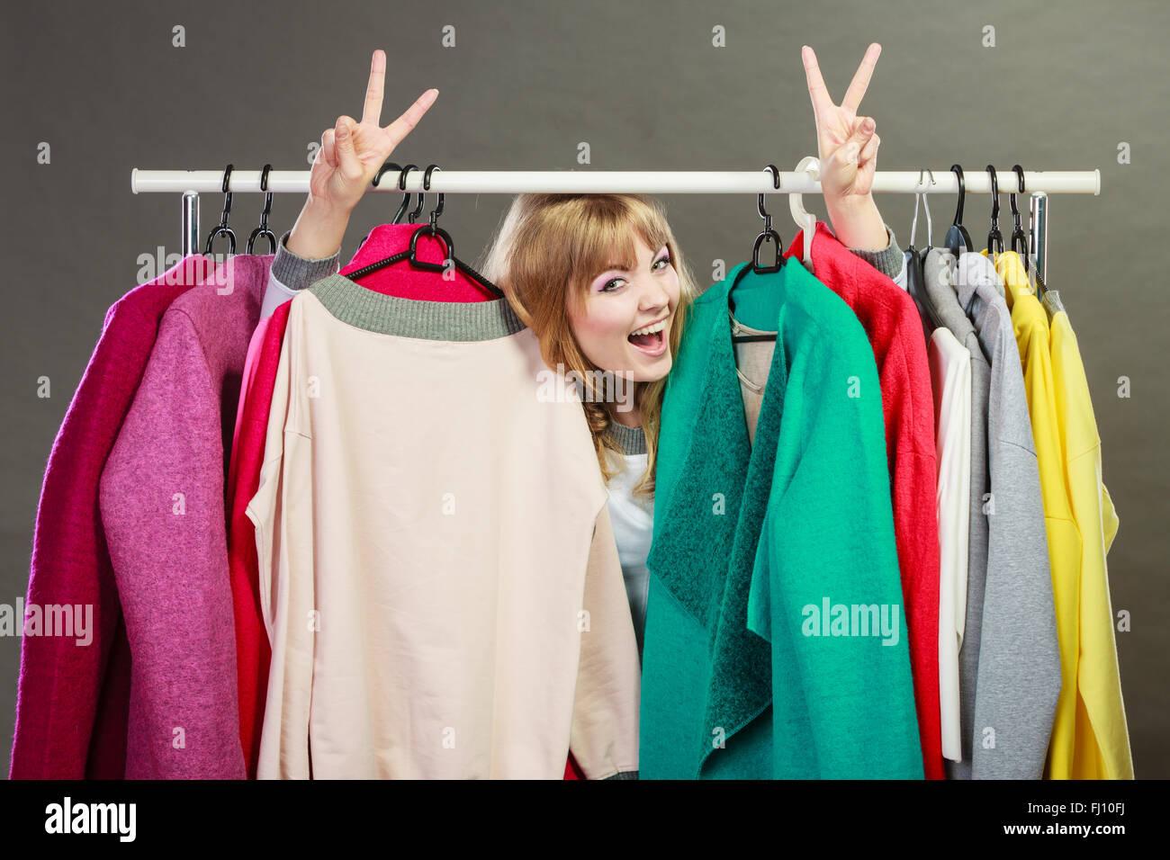 Pretty happy woman with clothing from wardrobe. Young undecided shopper ...