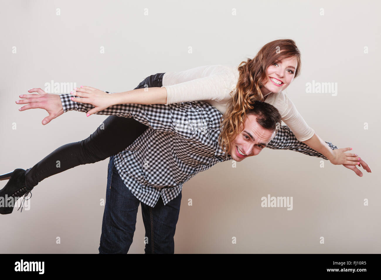 Smiling woman riding piggyback on man shoulders. Happy young couple having fun together in ...