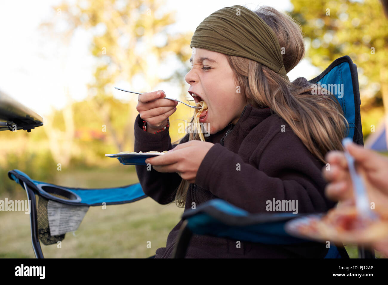 Girl eating spaghetti on a camping ground Stock Photo - Alamy