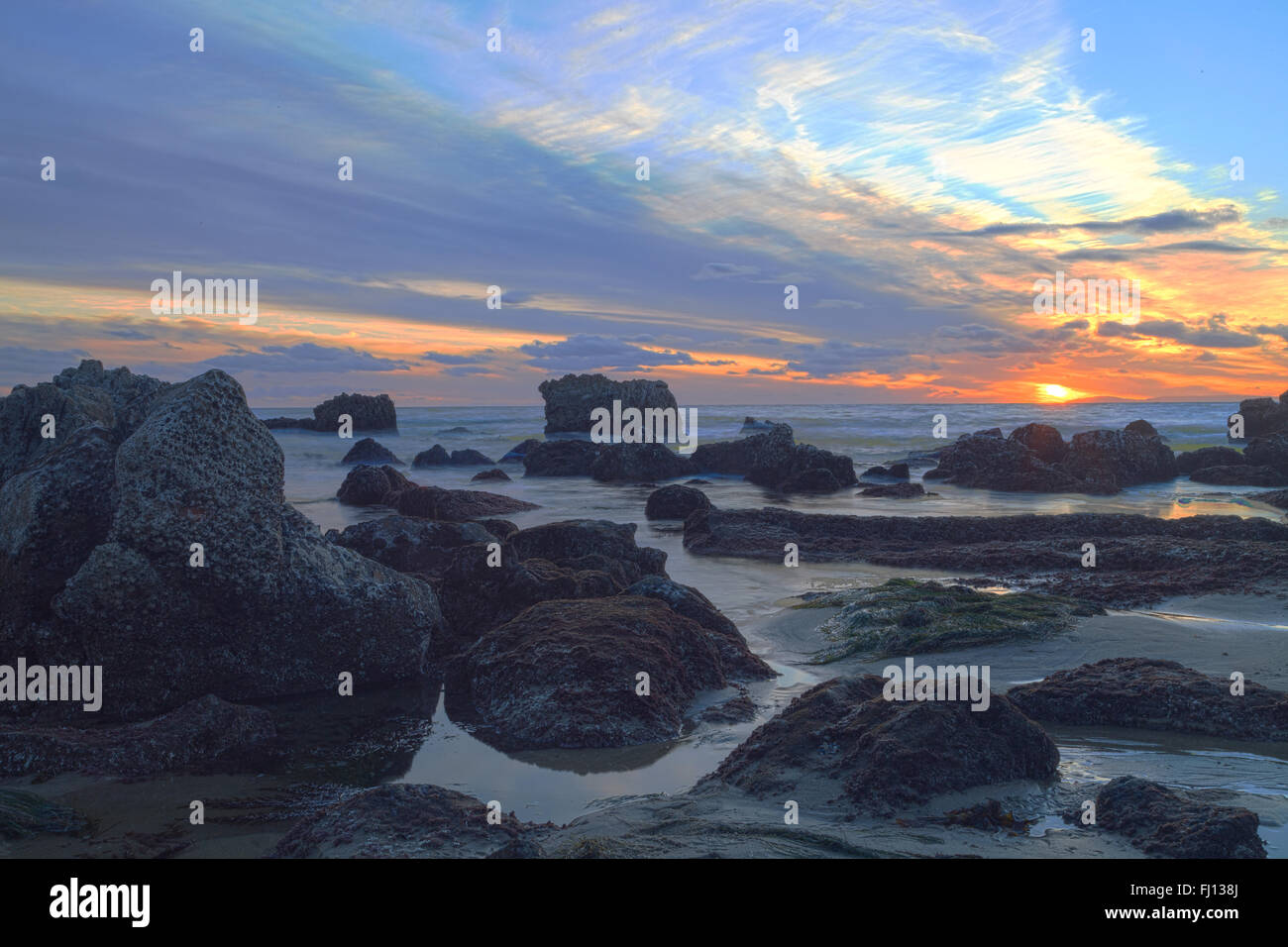 Long exposure of sunset over rocks, giving a mist like effect over ...