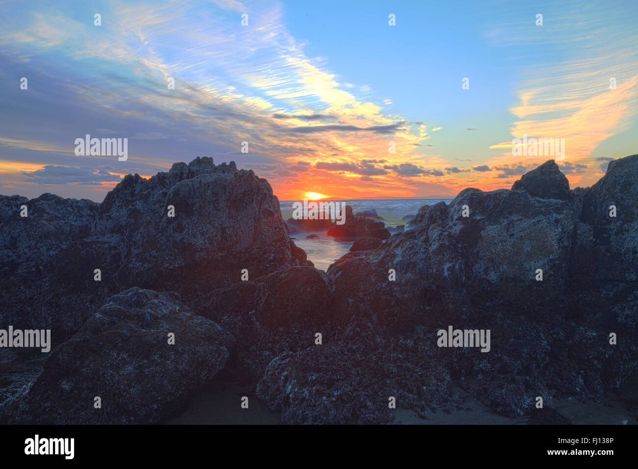 Long exposure of sunset over rocks, giving a mist like effect over ...