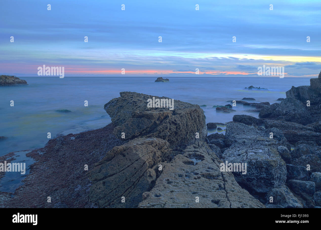 Long exposure of sunset over rocks, giving a mist like effect over ...