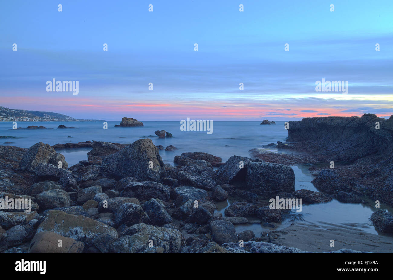 Long exposure of sunset over rocks, giving a mist like effect over ...
