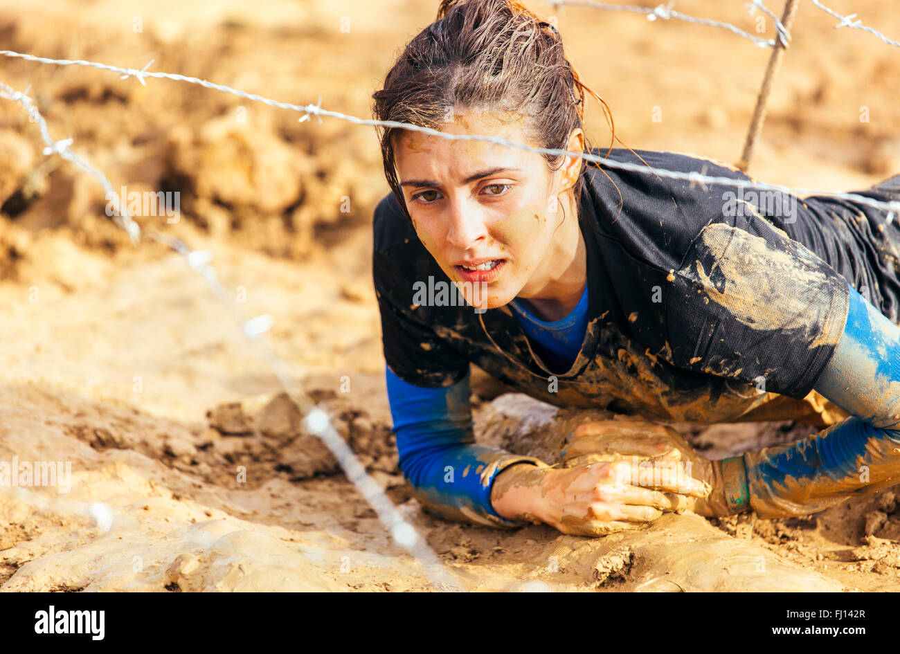 Participant in extreme obstacle race crawling under barbed wire Stock ...