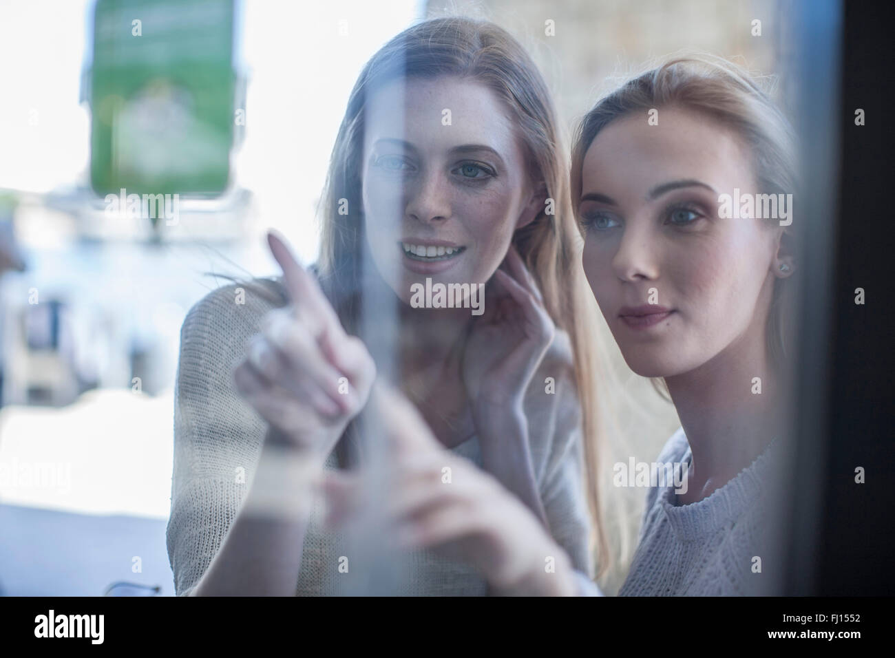 Young women looking through shop window Stock Photo - Alamy