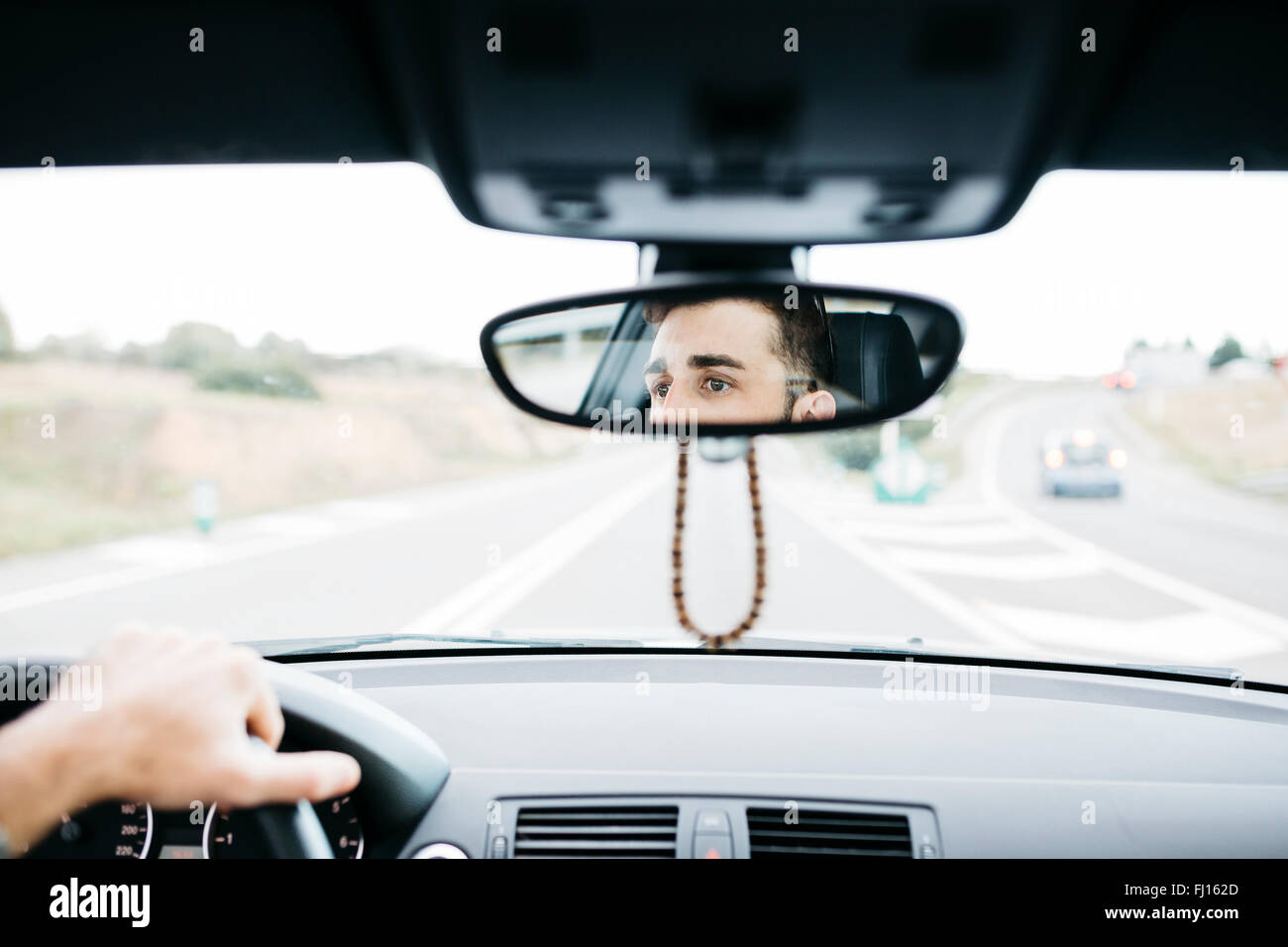 Young man driving a car, close up of rear mirror Stock Photo - Alamy