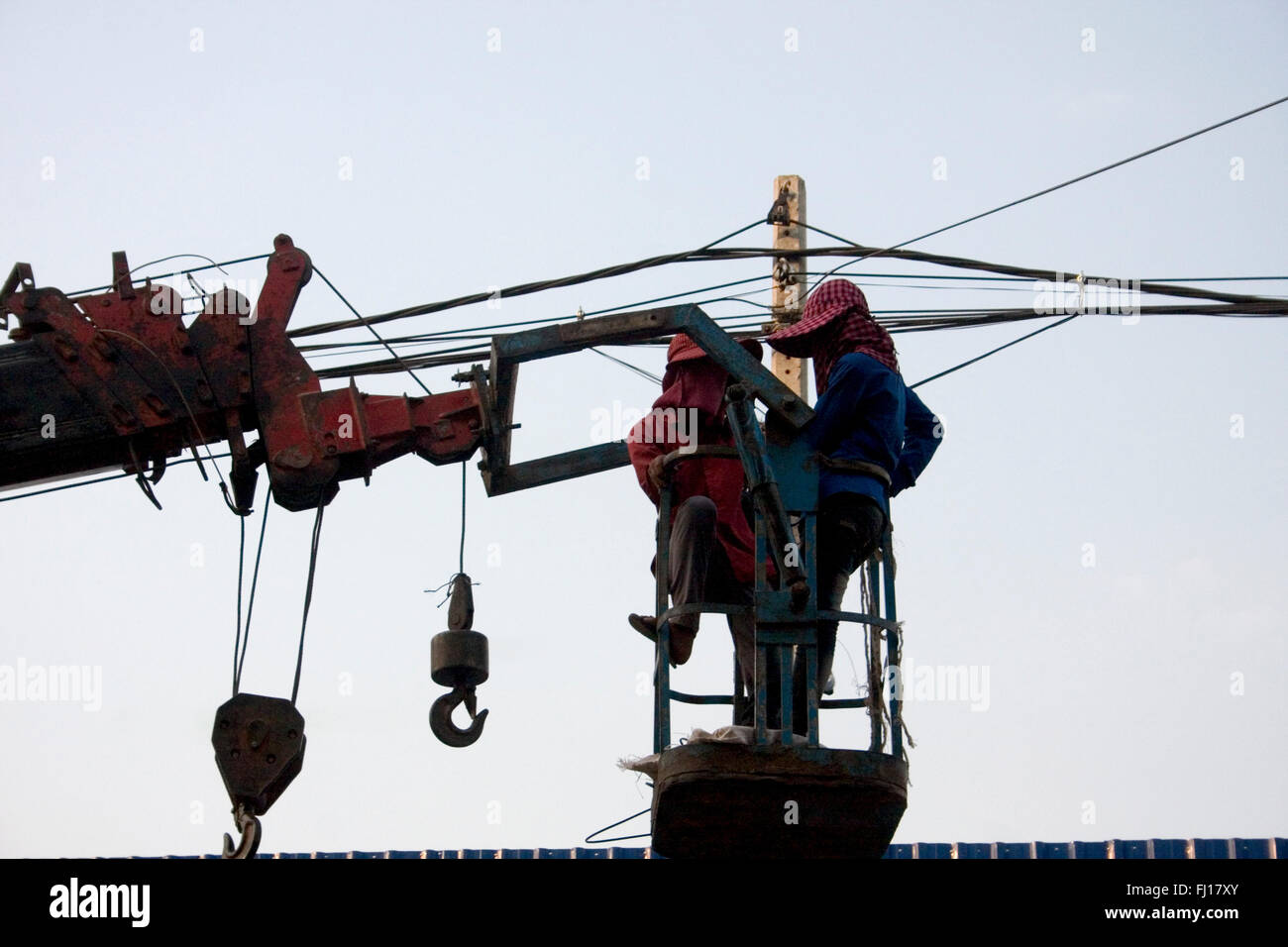 Two men are working on power and telephone lines above a new market in ...