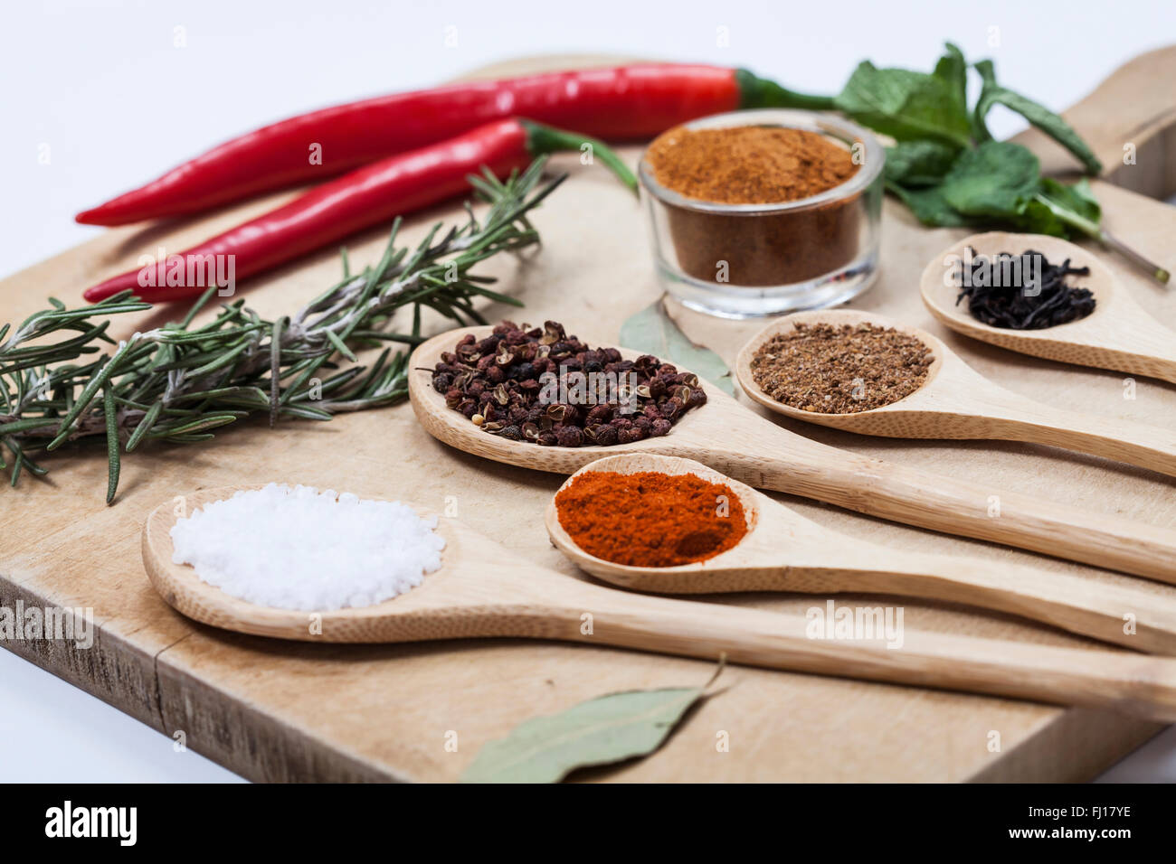 Various colorful spices on kitchen spoons over grunge wooden ...