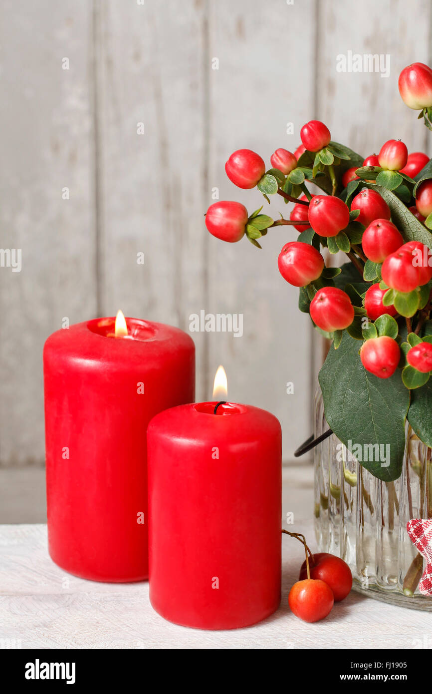 Rad candles and bouquet of hypericum plants (twigs with red berries) on ...