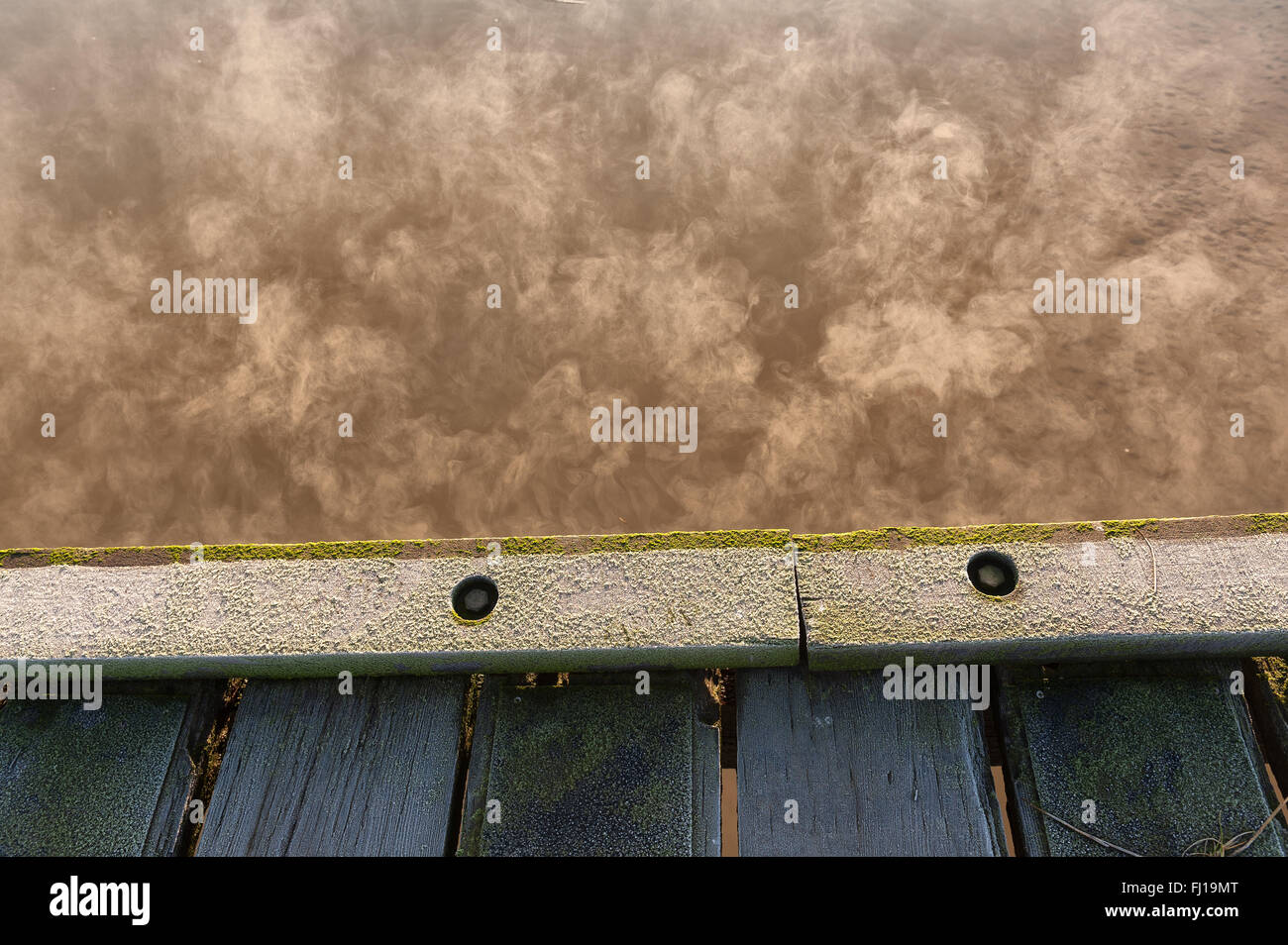 billowing steam evaporating from heated frozen water causeway on river ...