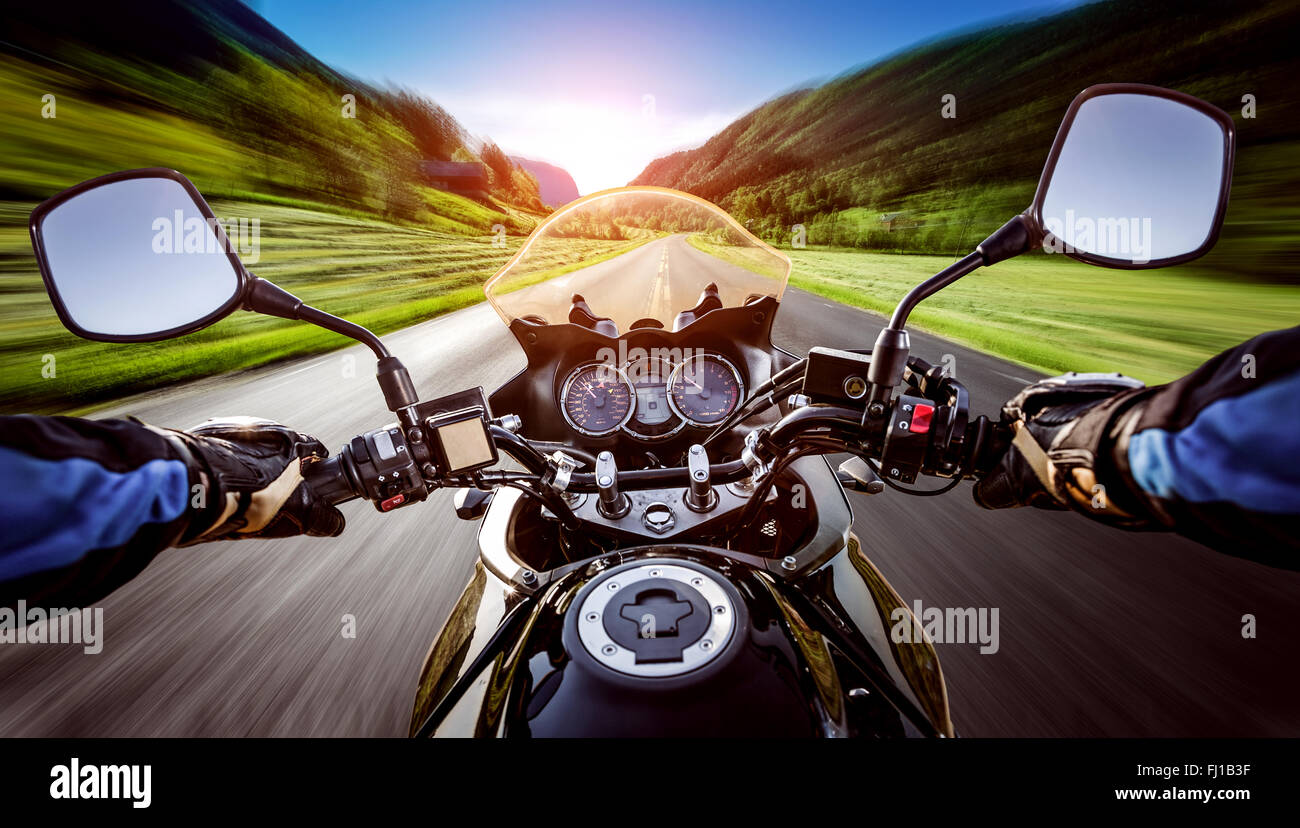 Biker driving a motorcycle rides along the asphalt road. First-person ...