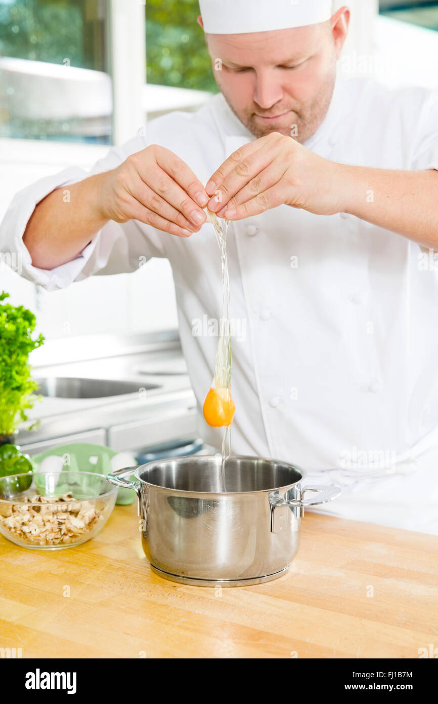Chef cracking egg in large kitchen Stock Photo - Alamy