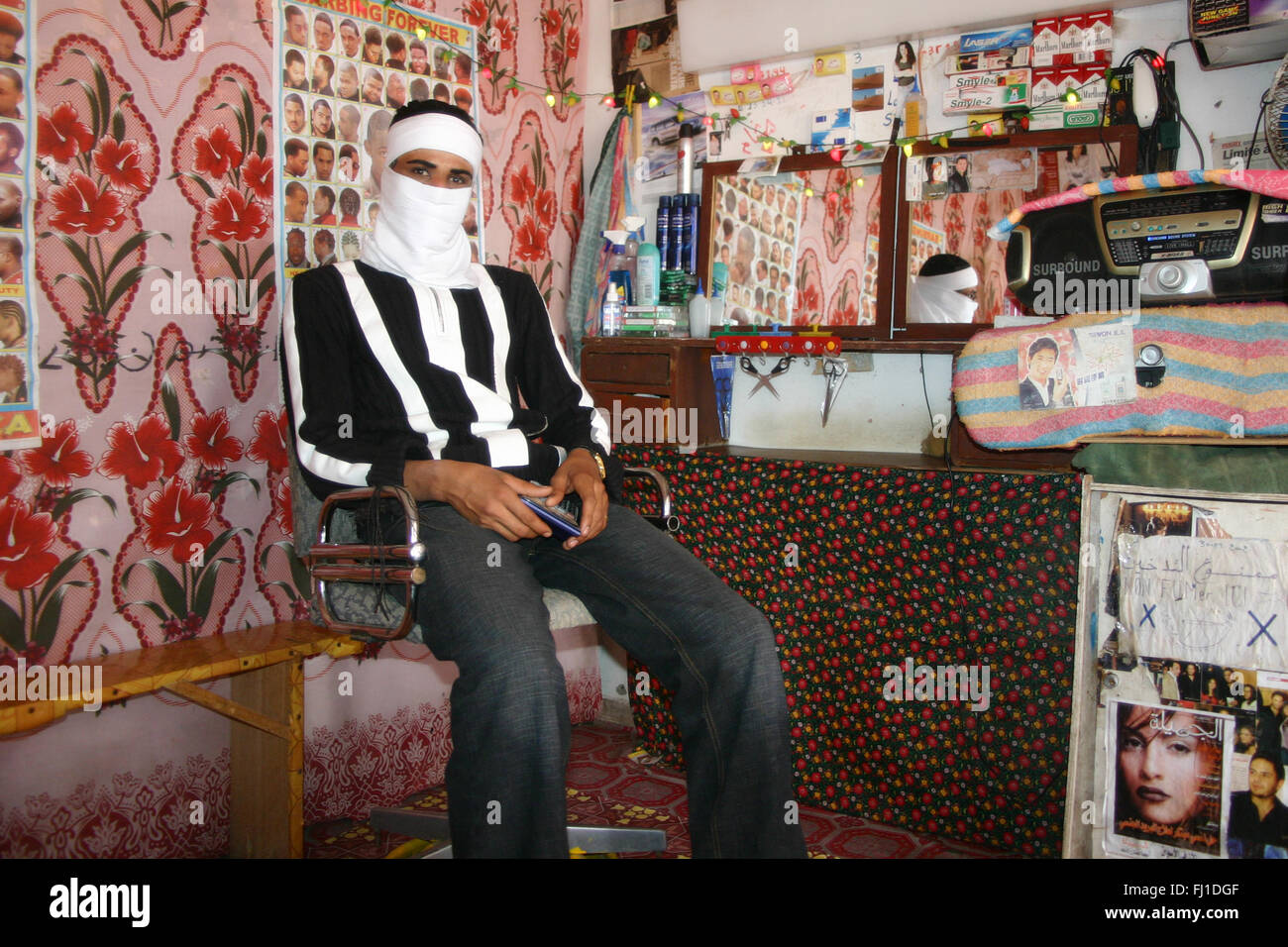 Hairdresser with covered face in his traditional salon in Atar city ...
