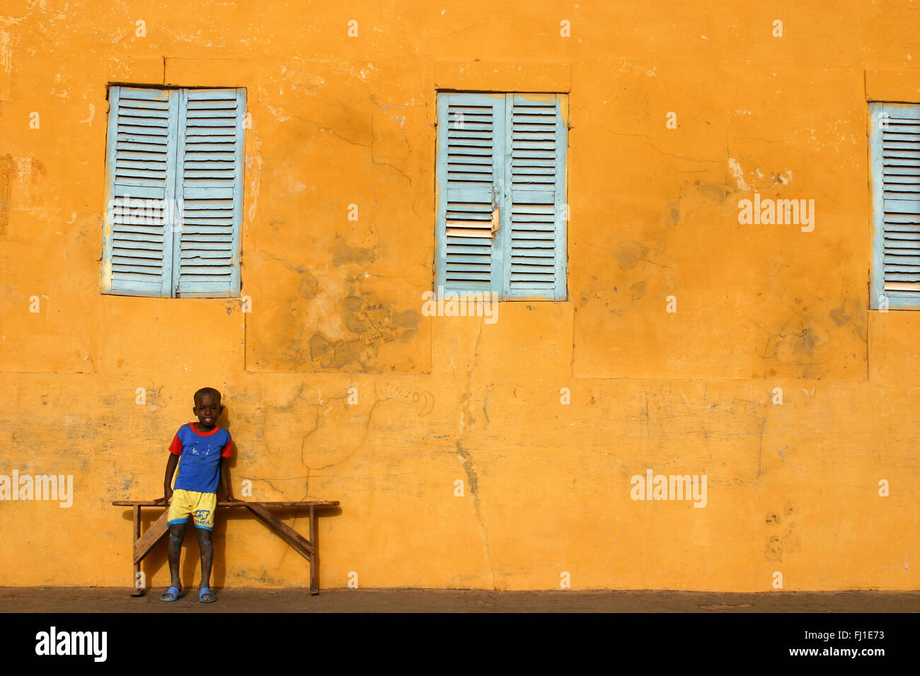 A boy is posing in front of a wall of a typical colonial house painted ...
