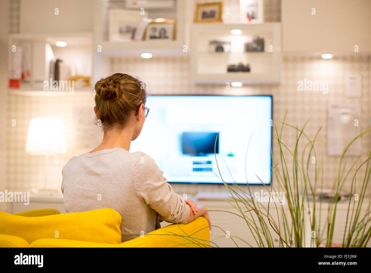Pretty, young woman watching TV at home (color toned image; shallow DOF ...