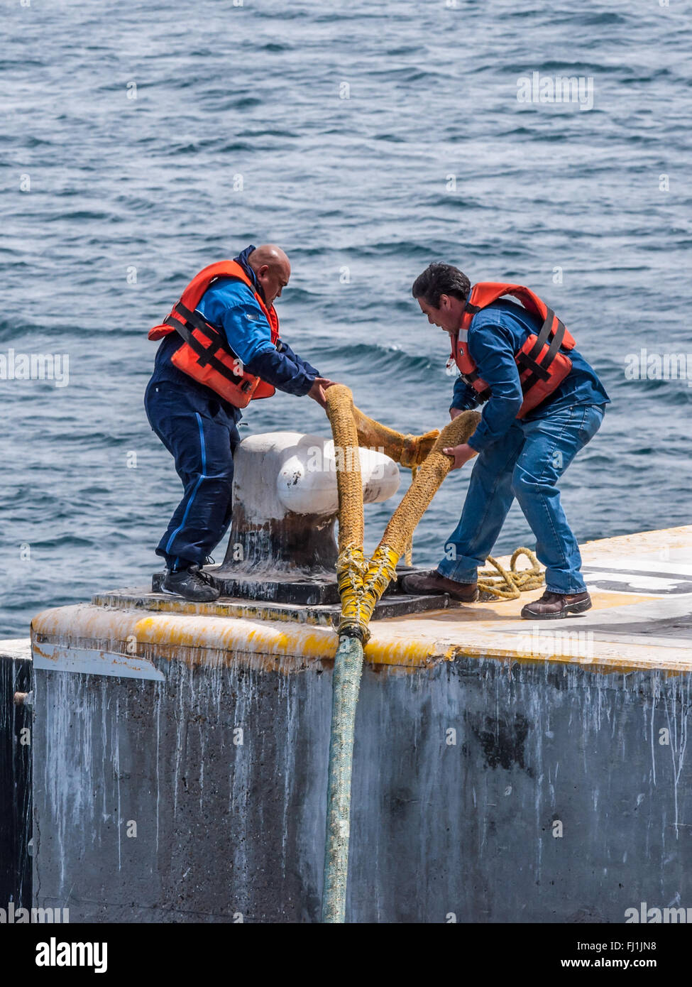 On the mooring platform a workers casts off the mooring cable of a ship ...