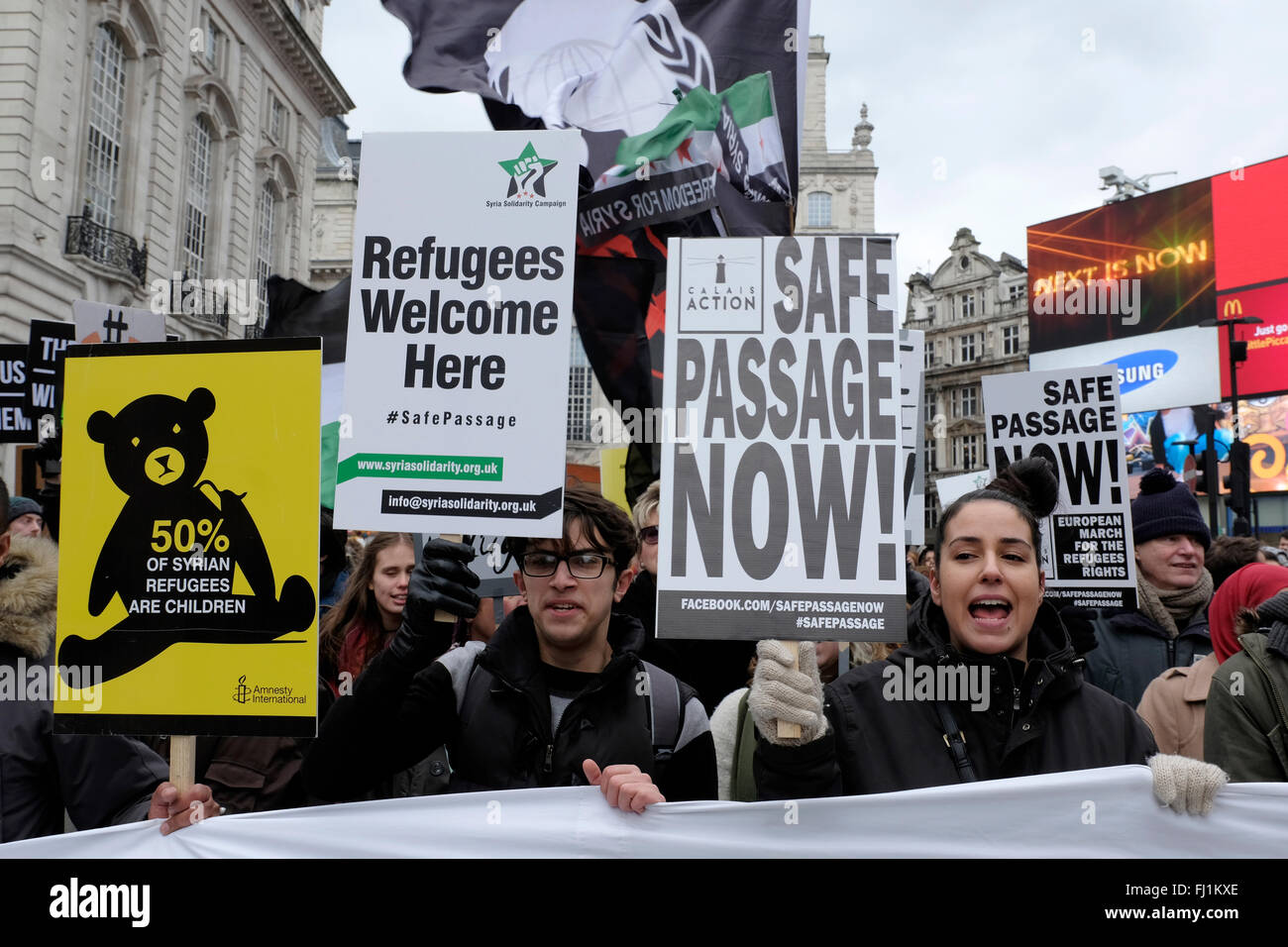 Protesters holding placards reading "Refugees welcome here, safe ...