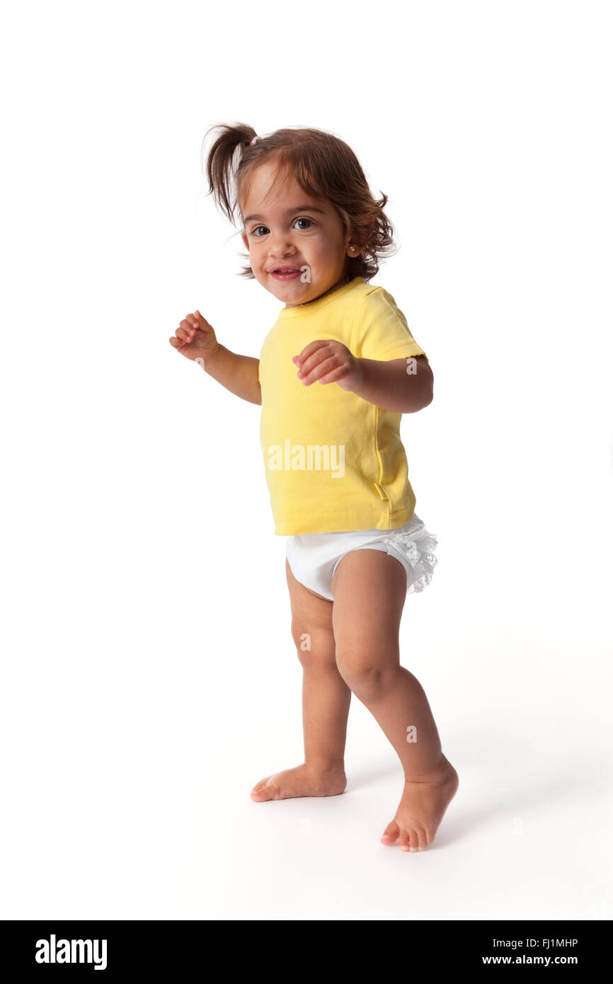 Baby girl standing on her own on white background Stock Photo - Alamy