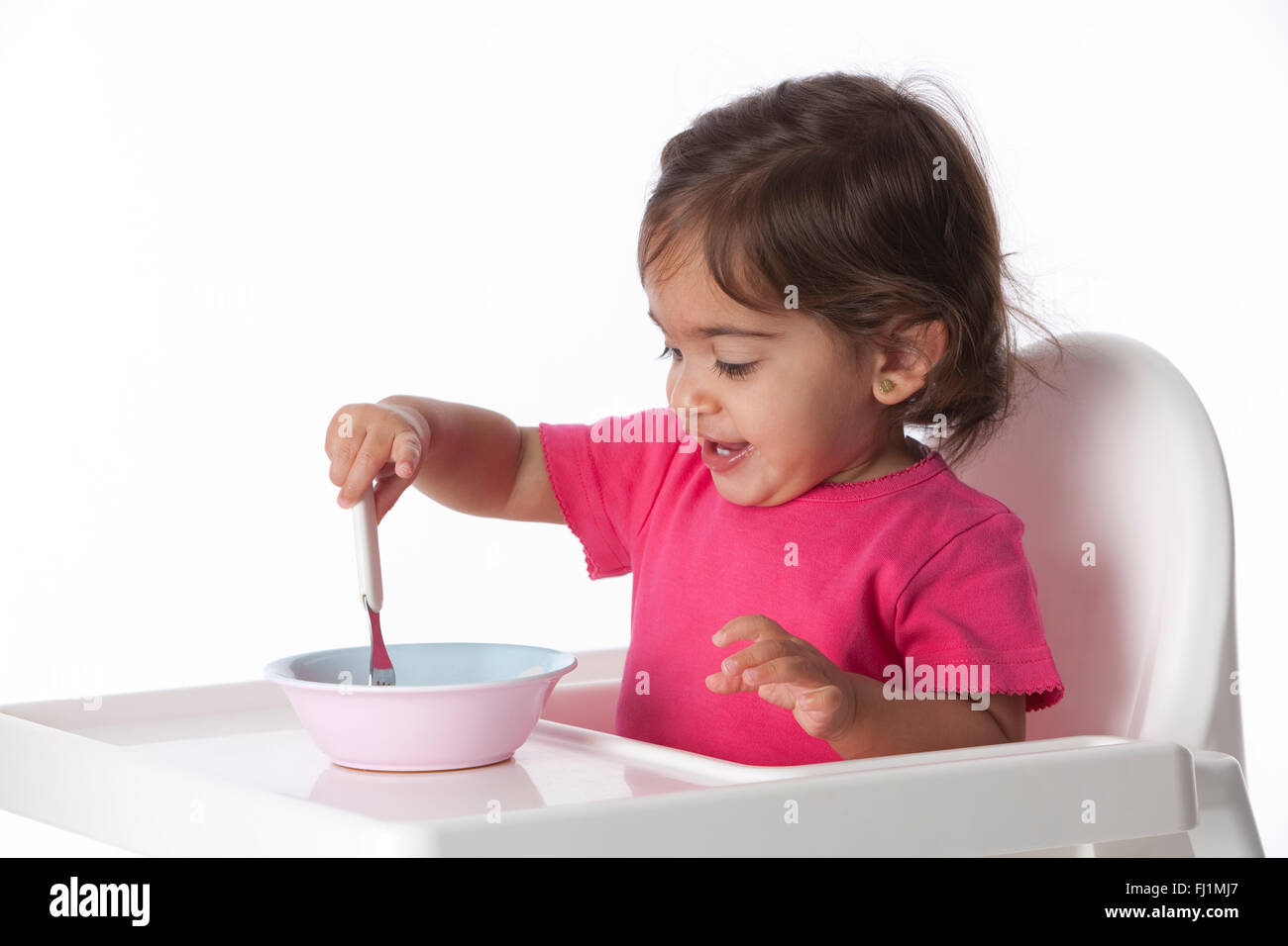 Happy Baby girl is eating by herself on white background Stock Photo ...