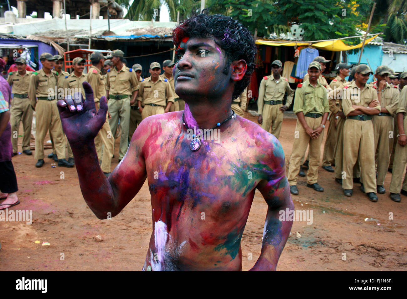 A man covered with Holi colors during celebrations is dancing in front ...
