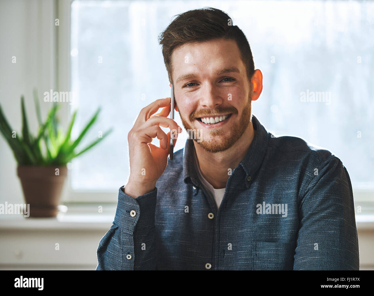 Smiling man talking on phone looking happy into camera Stock Photo - Alamy