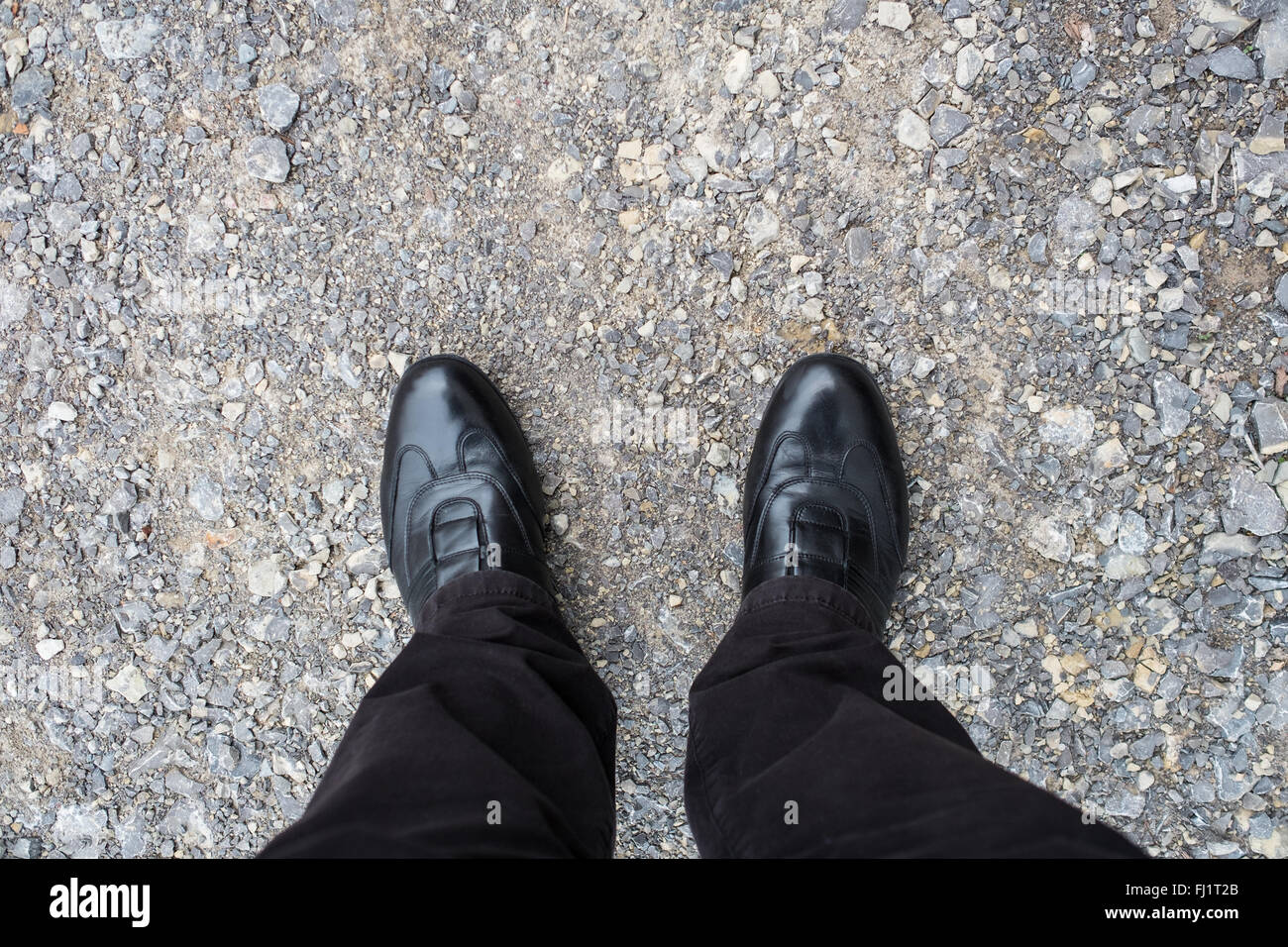 Legs with black shoes on pebbles and stones Stock Photo - Alamy