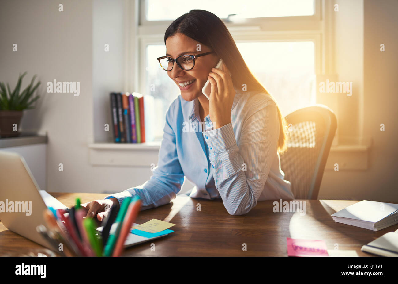 Business woman working on laptop smiling talking on phone sun coming ...