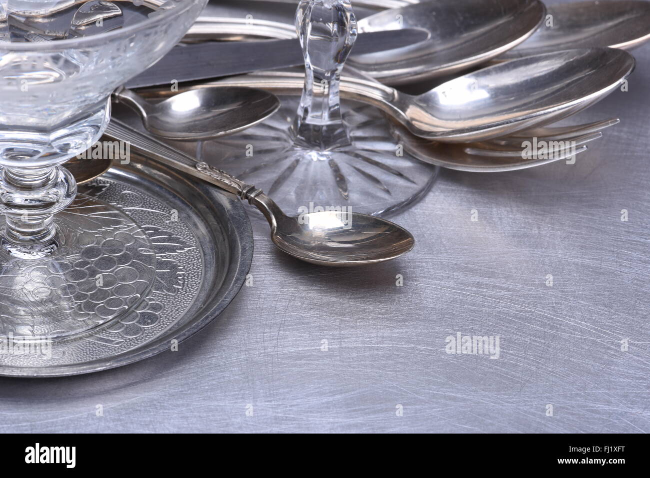 Silver table setting with fork, knife, spoon and glass on gray metal ...