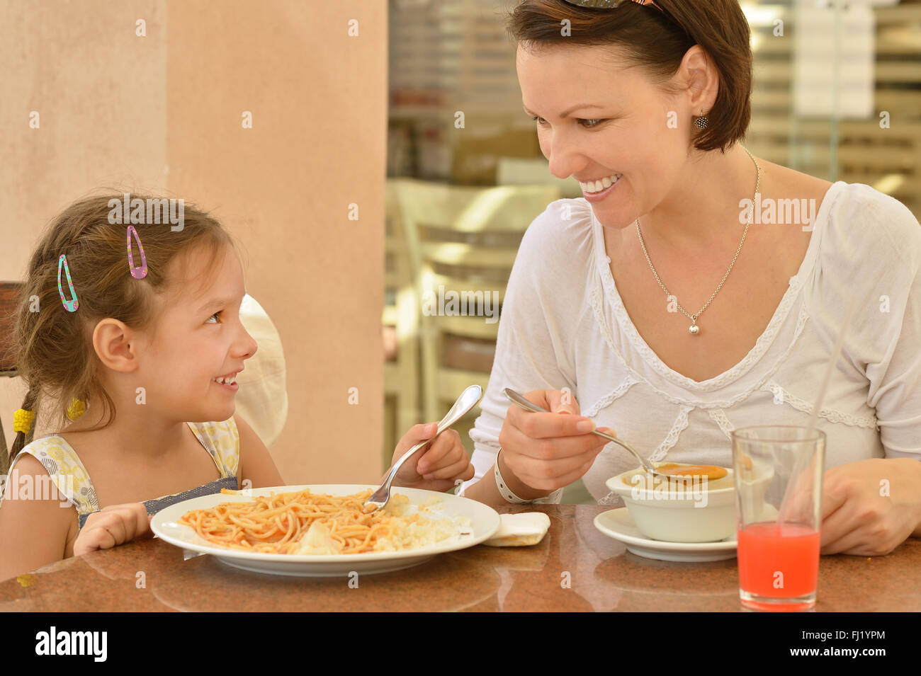 girl with mother eating at table Stock Photo - Alamy
