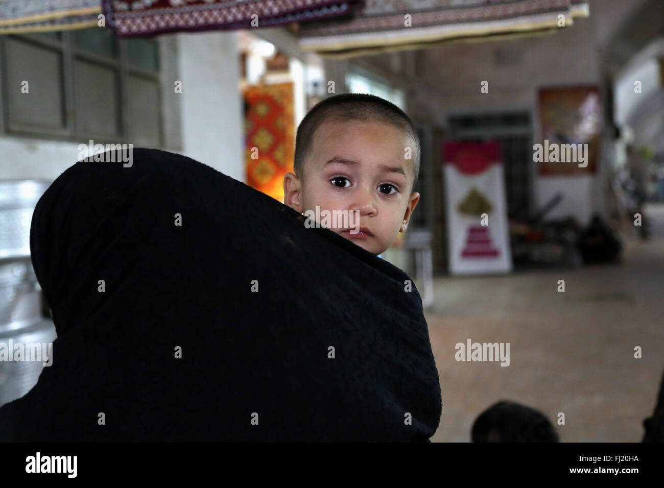 Portrait of a young child in the market of Yazd with his head covered ...