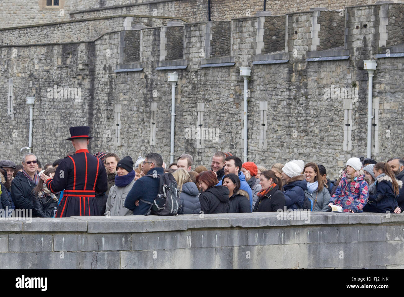 Traditional Beefeater giving a tour to tourists, The Tower of London ...
