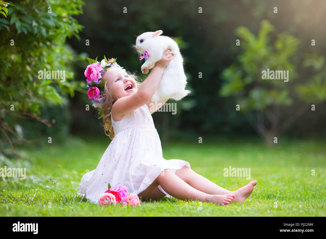 Girl playing with real rabbit in sunny garden. Child and bunny on ...