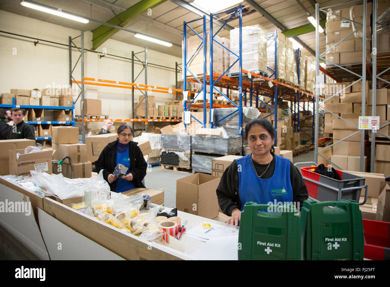 Factory workers pack boxes of First Aid kits Stock Photo - Alamy