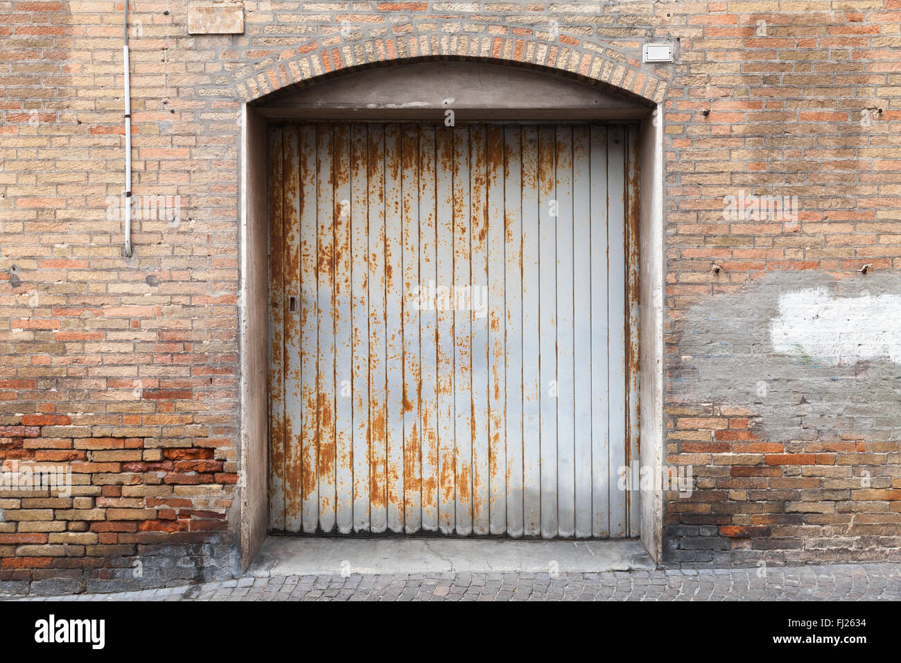Rusted grungy metal gate in old brick wall, background photo texture ...