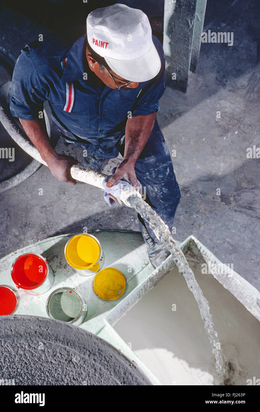 African American man mixing water into paint in industrial factory ...