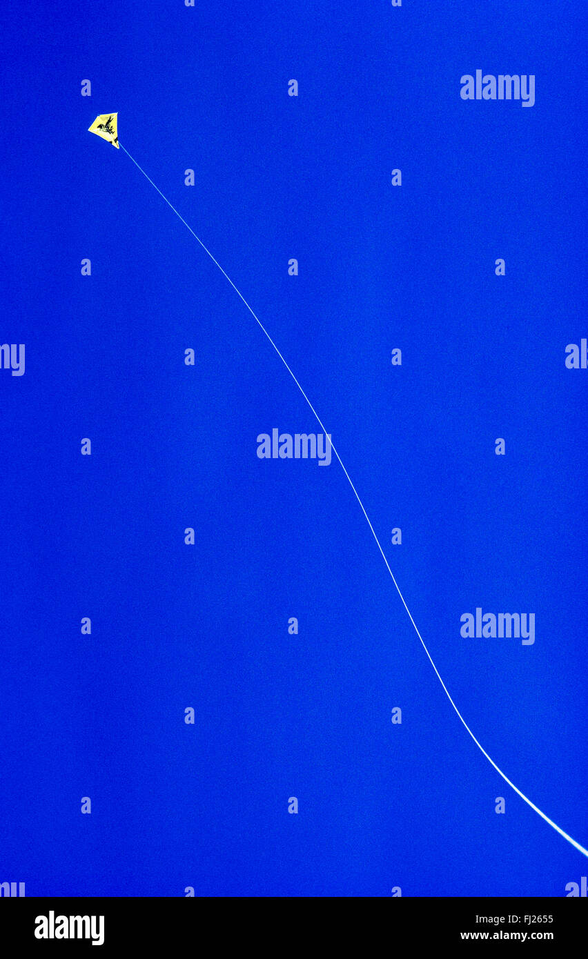 A bright yellow toy kite flies high in the deep blue sky and inspires a ...